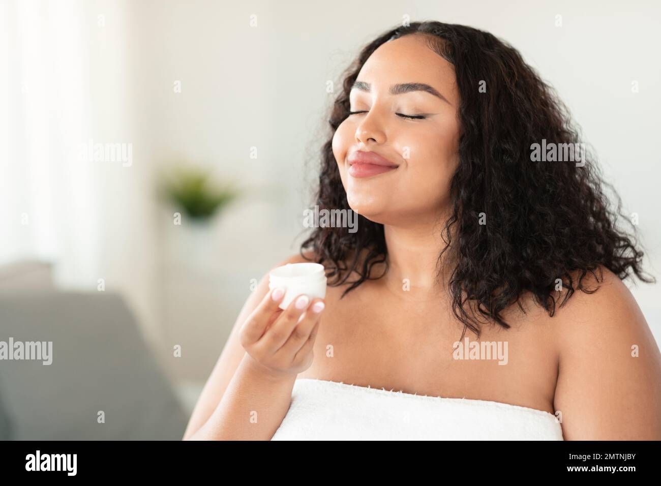 Cosmetics and skin care concept. Positive overweight lady holding cream ...