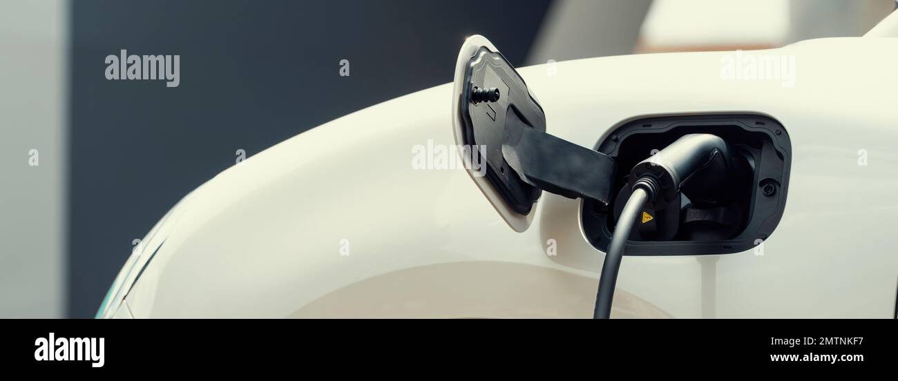 Closeup electric vehicle plugged-in with cable from charging point ...