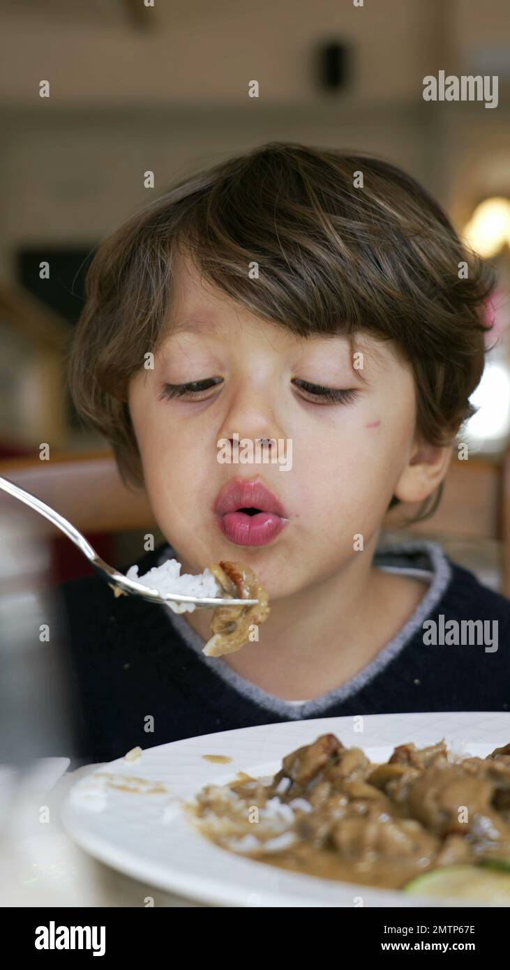 Mother feeds food to little boy son. Child blowing hot food sitting at ...