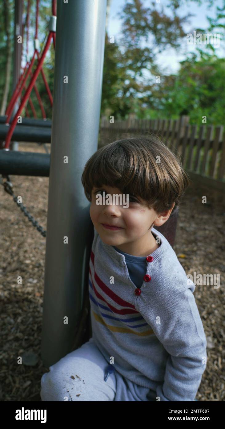 One adorable little boy sitting at playground park structure smiling at ...