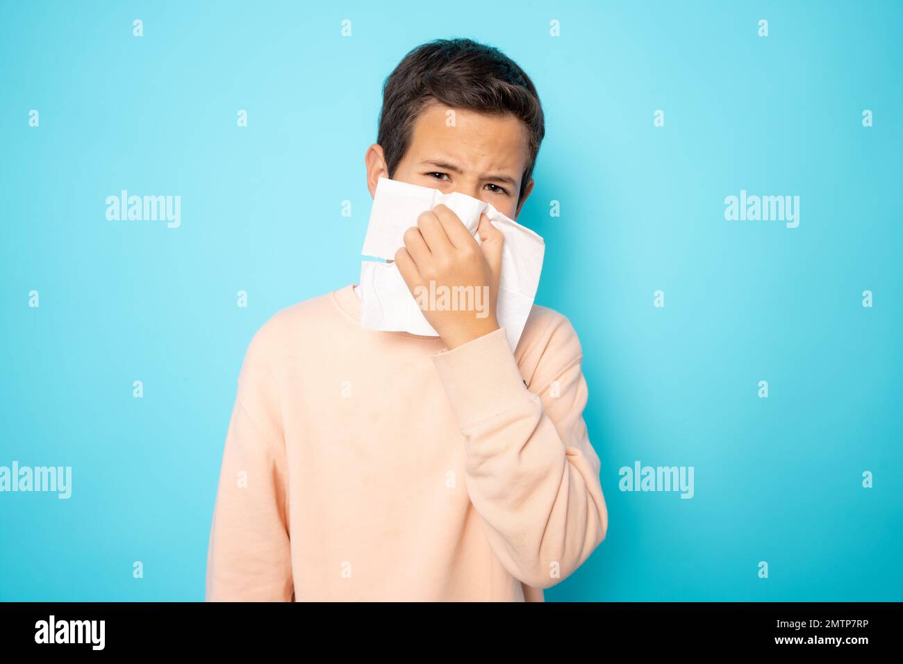 Child with runny nose blows it into a paper handkerchief. illness flu ...
