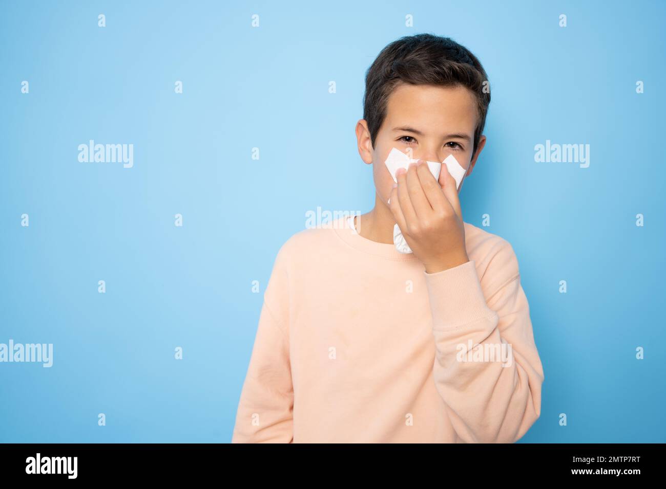 Child with runny nose blows it into a paper handkerchief. illness flu ...