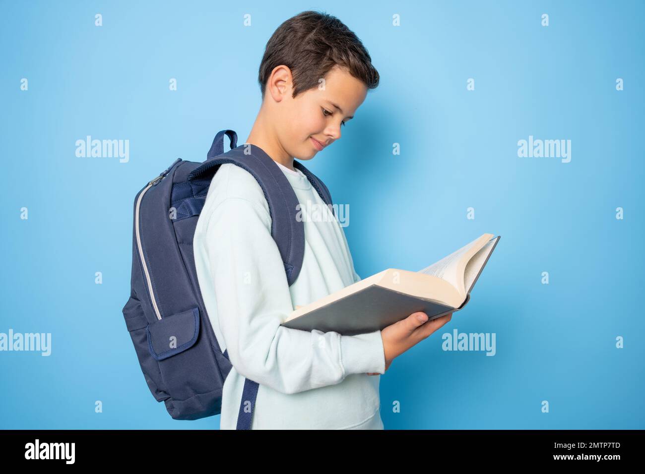 Image of young happy boy reading book and smiling isolated over blue ...