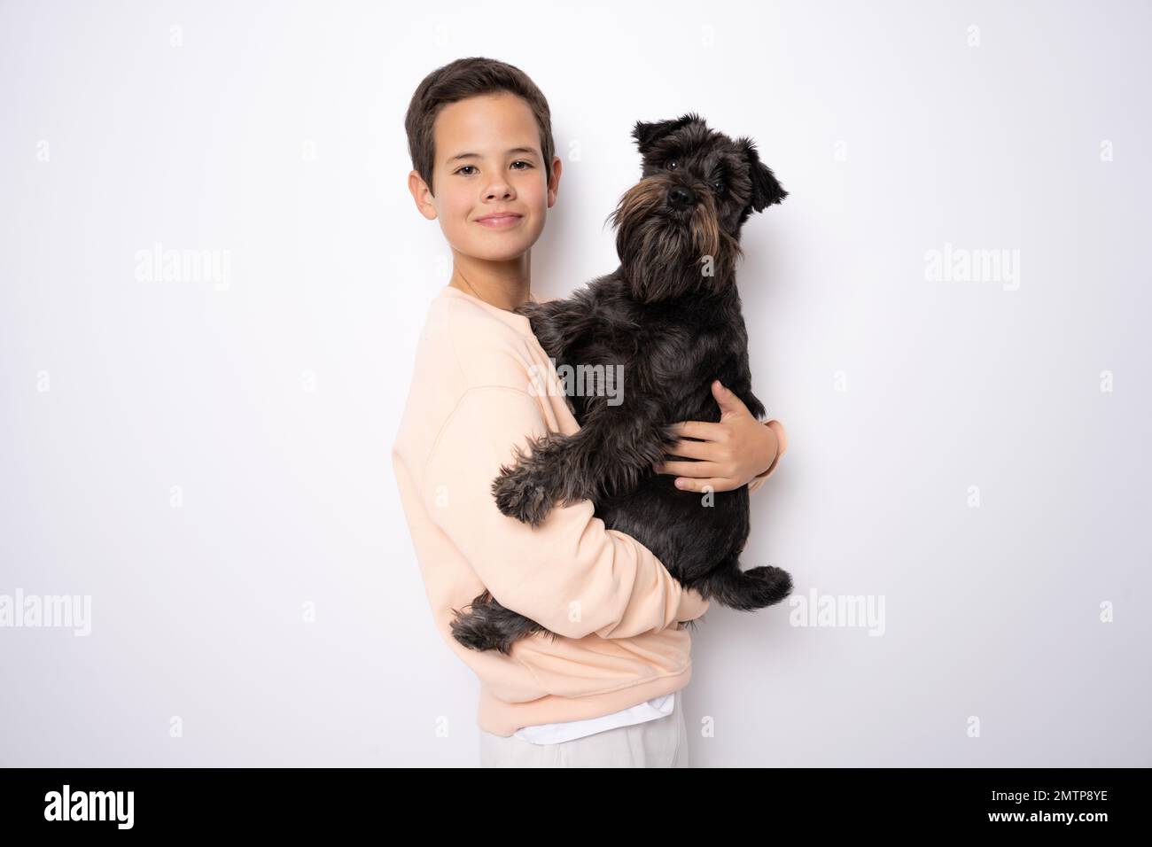 Dog Schnauzer and smiling boy hugs her with tenderness and look at ...