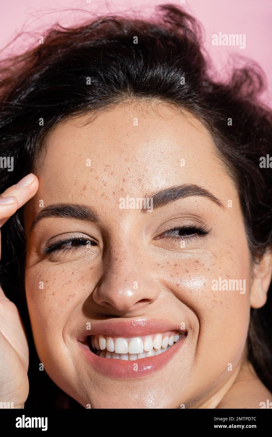 Close up view of positive woman with freckles touching skin isolated on ...