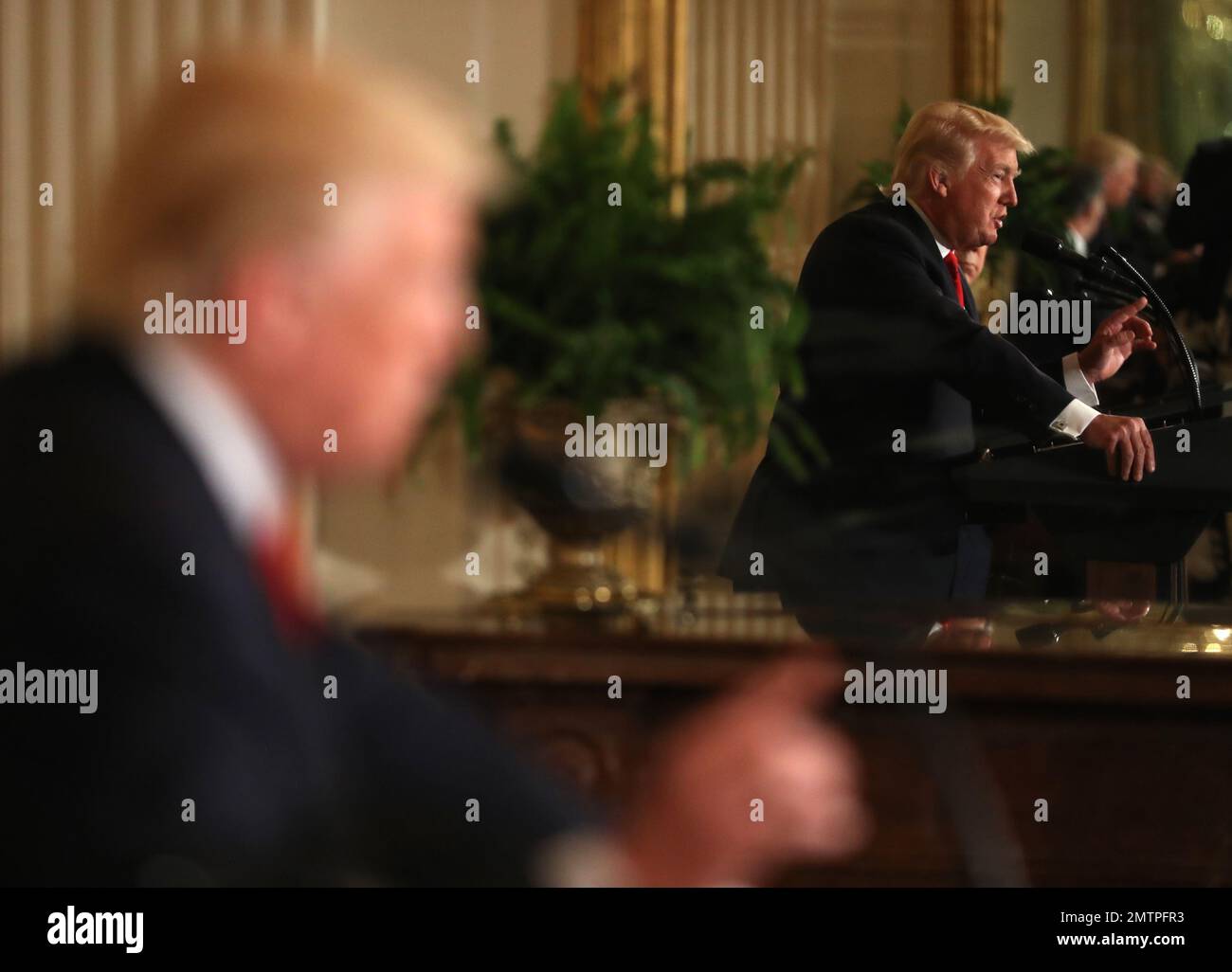 President Donald Trump is reflected in a mirror during a news ...