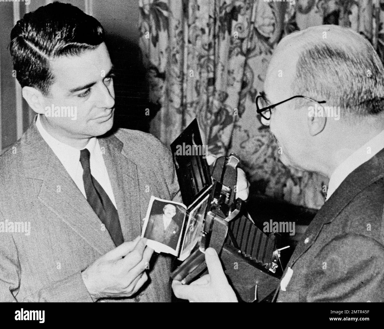 Dr. Edwin H. Land, left, inventor of the Polaroid Land Camera, peels ...