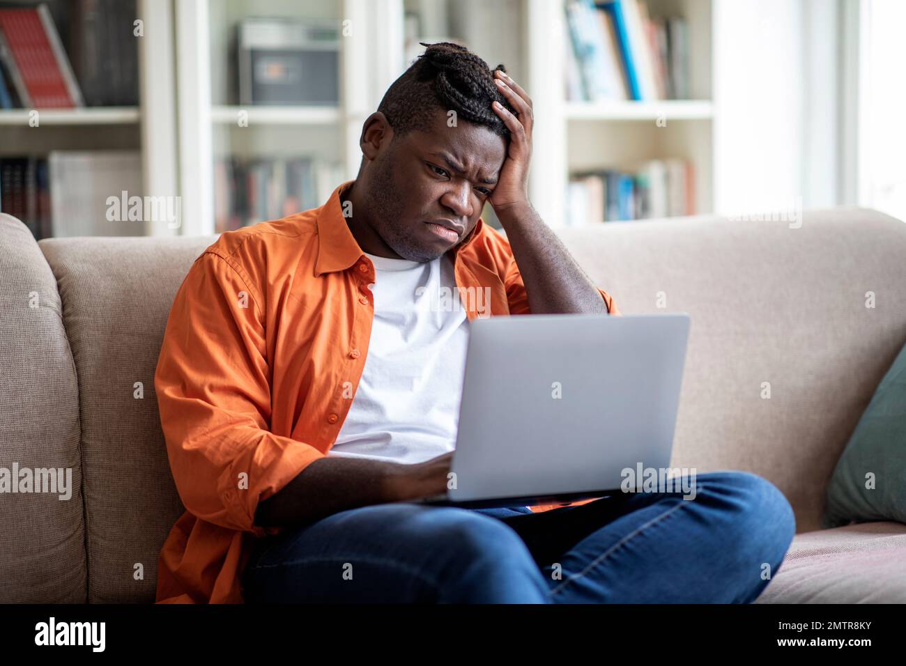 Stressed young upset black man using laptop at home Stock Photo - Alamy