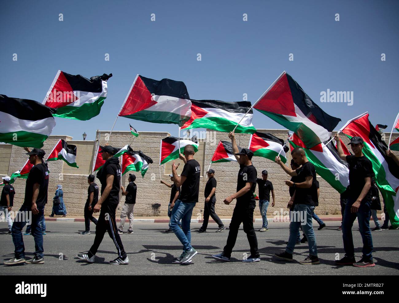 Palestinians carry national flags as they stage a rally to mark the ...