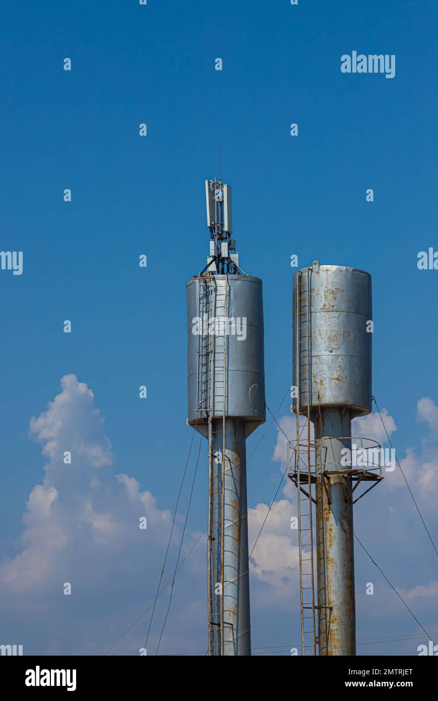 Two old style water towers surrounded by trees, with clear blue skies ...