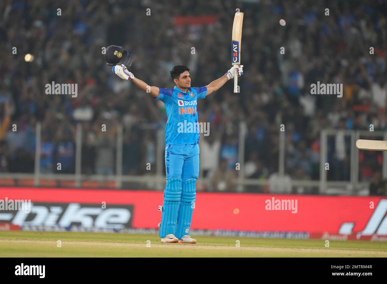 India's Shubhman Gill raises his bat and helmet to celebrate scoring a ...