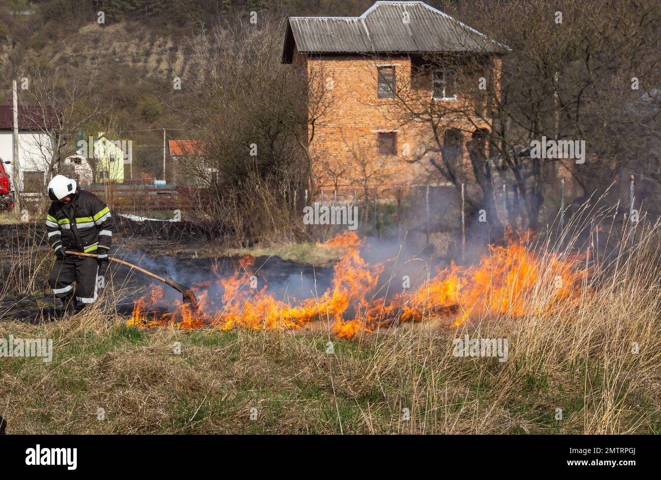 spring fire, burning dry grass near buildings in the countryside ...