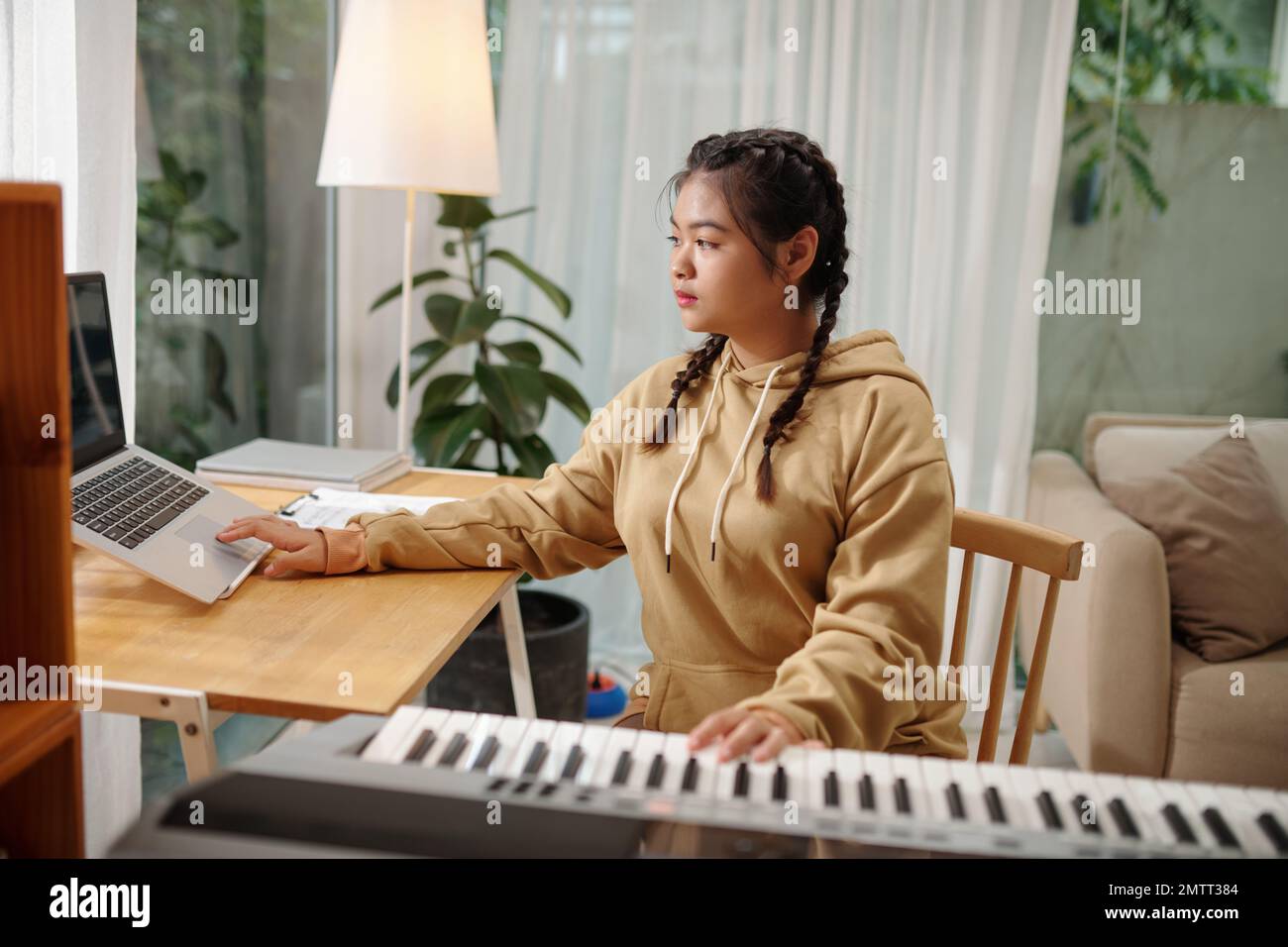 Teenage girl following tutorial on laptop when learning playing ...