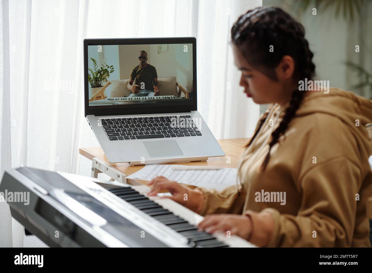 Laptop with music teacher on screen on desk of girl learning how to ...