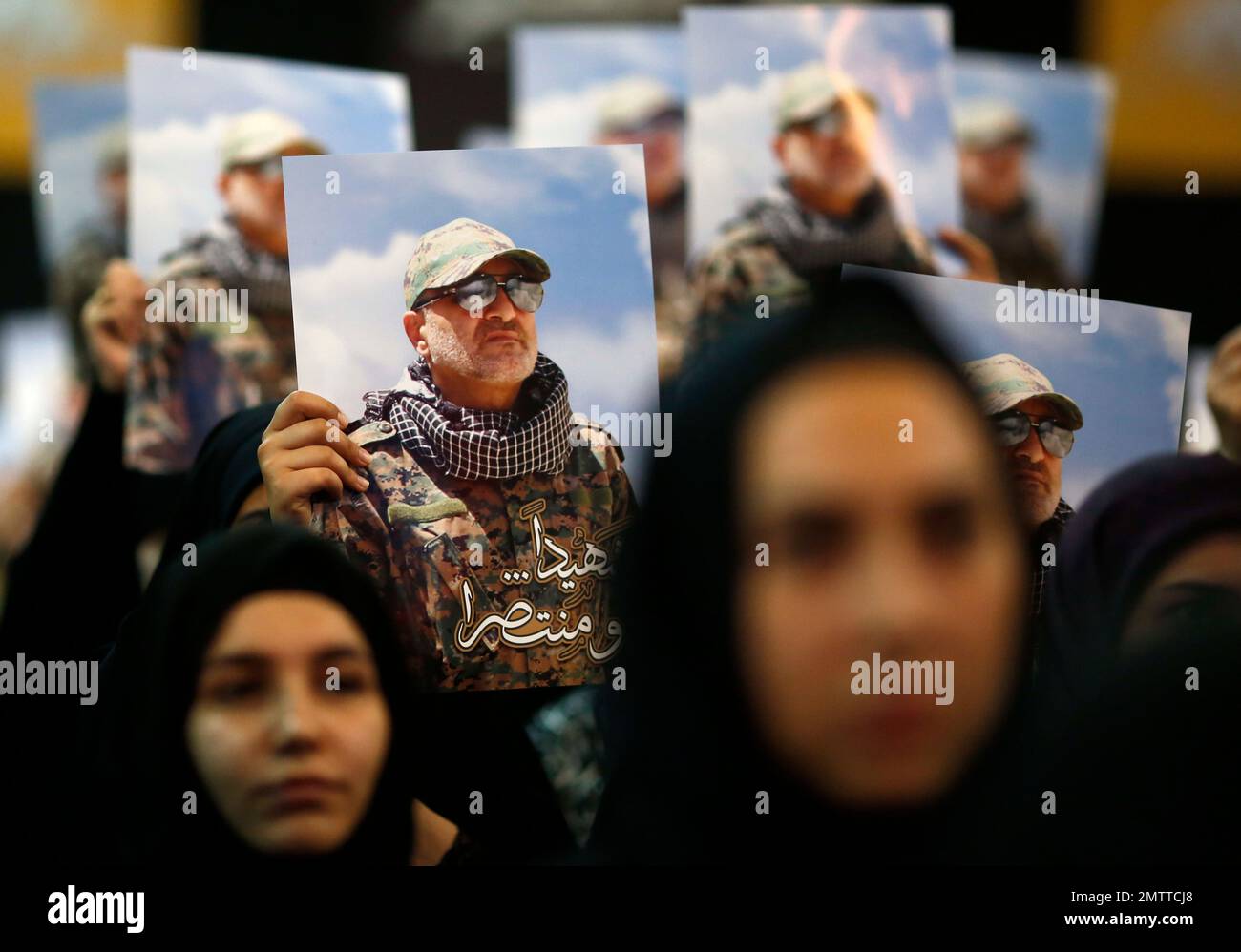 Women hold pictures of Hezbollah slain top commander Mustafa Badreddine ...