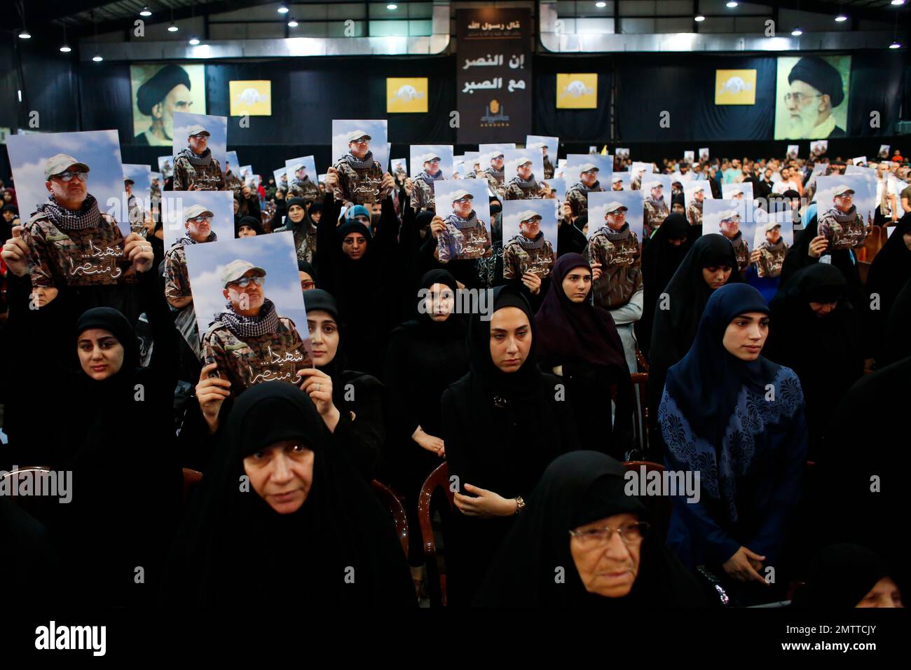 Women hold pictures of Hezbollah slain top commander Mustafa Badreddine ...