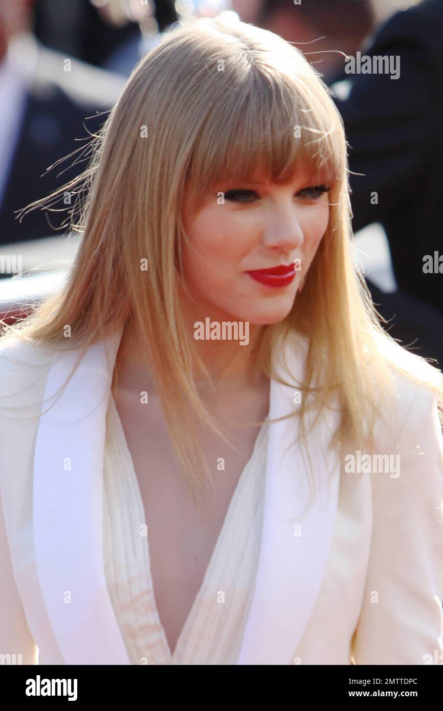 Wearing a white pant suit with tan high heels, singer Taylor Swift ...