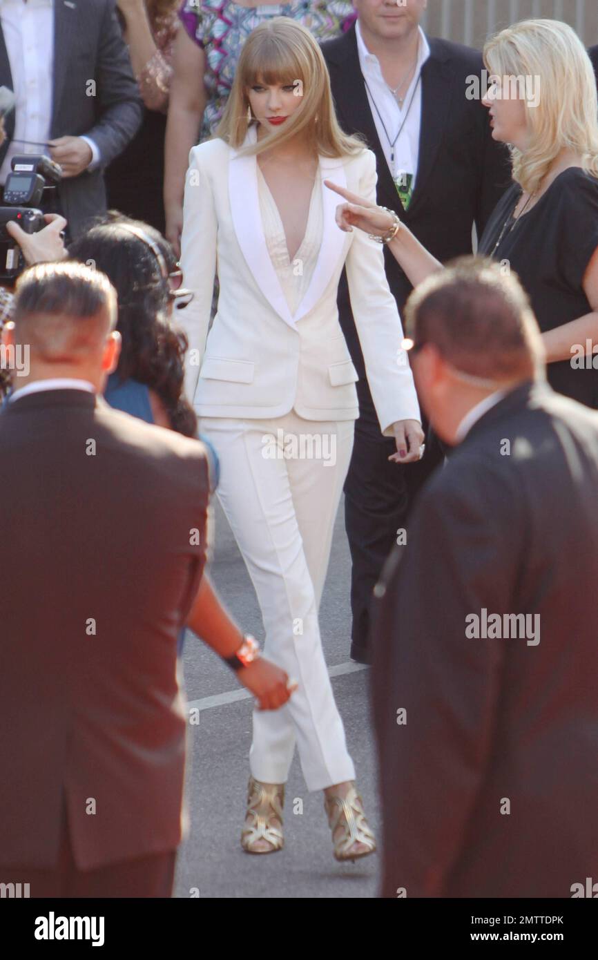 Wearing a white pant suit with tan high heels, singer Taylor Swift ...