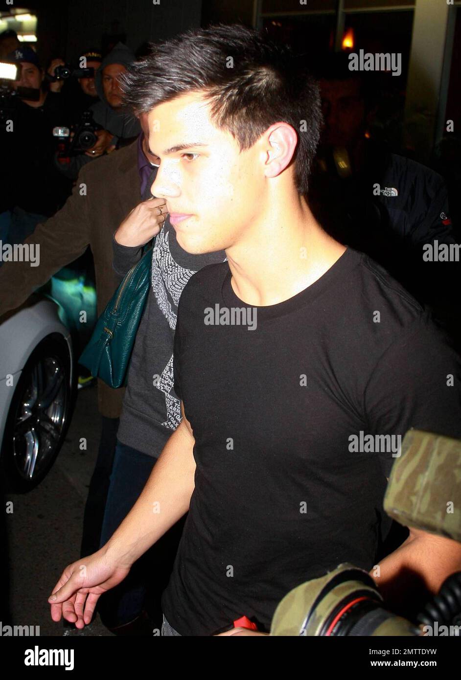 Taylor Lautner walks with his arm around Taylor Swift, doing nothing to ...