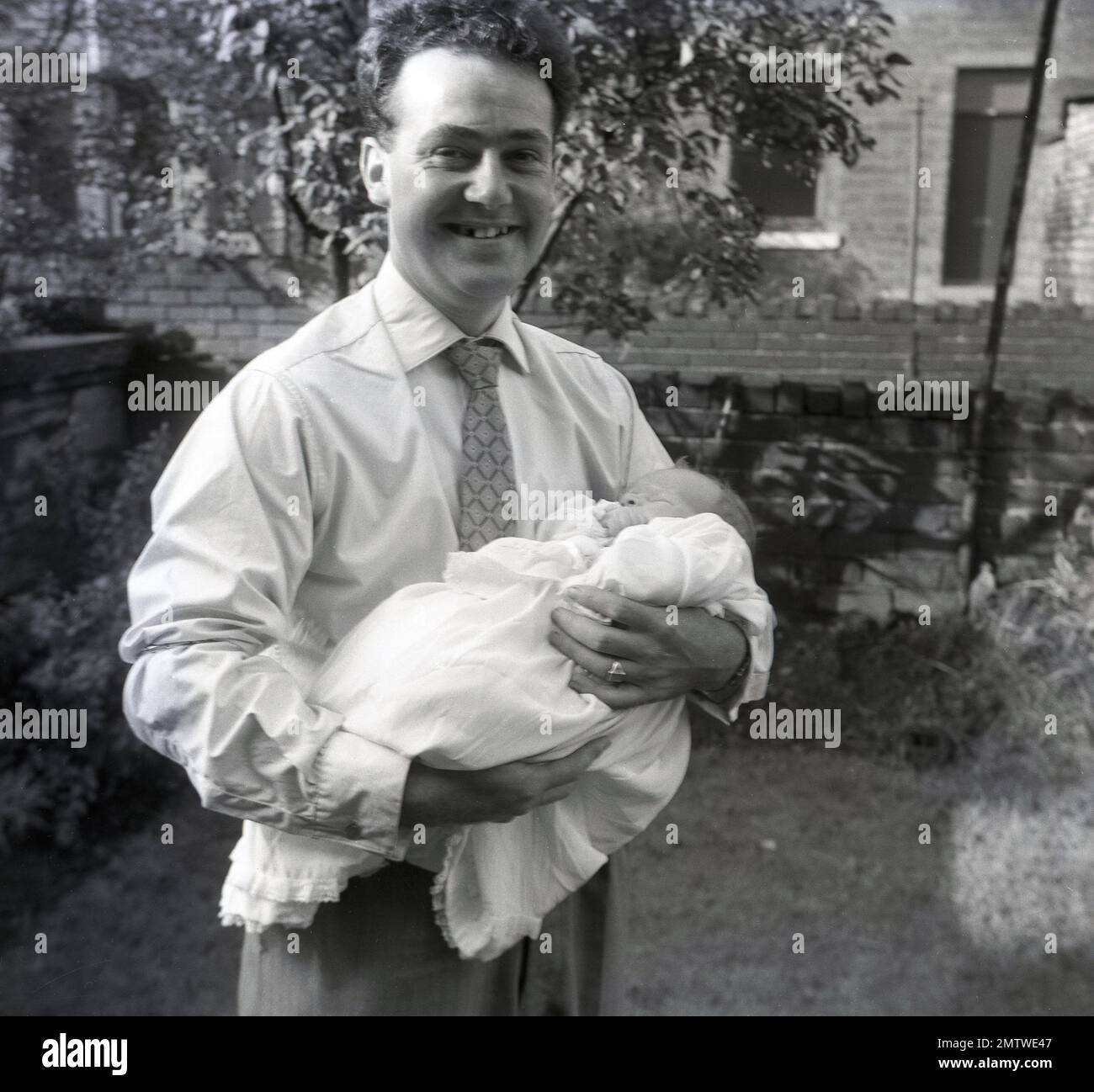 1950s, historical, with a big smile on his face, a father holding his ...
