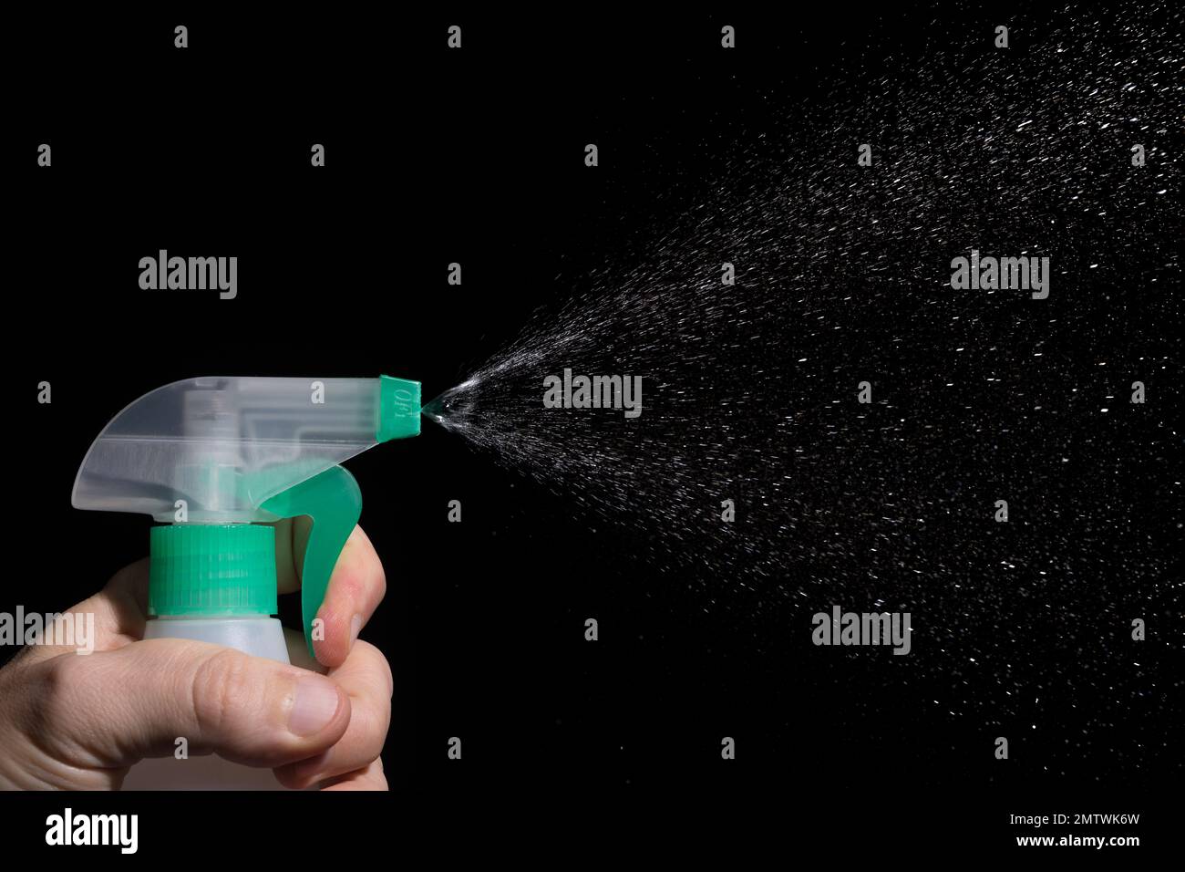 A hand spraying water on the black background Stock Photo - Alamy