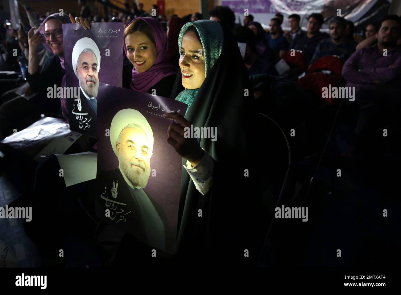 Supporters of Iranian President Hassan Rouhani hold his posters in a ...