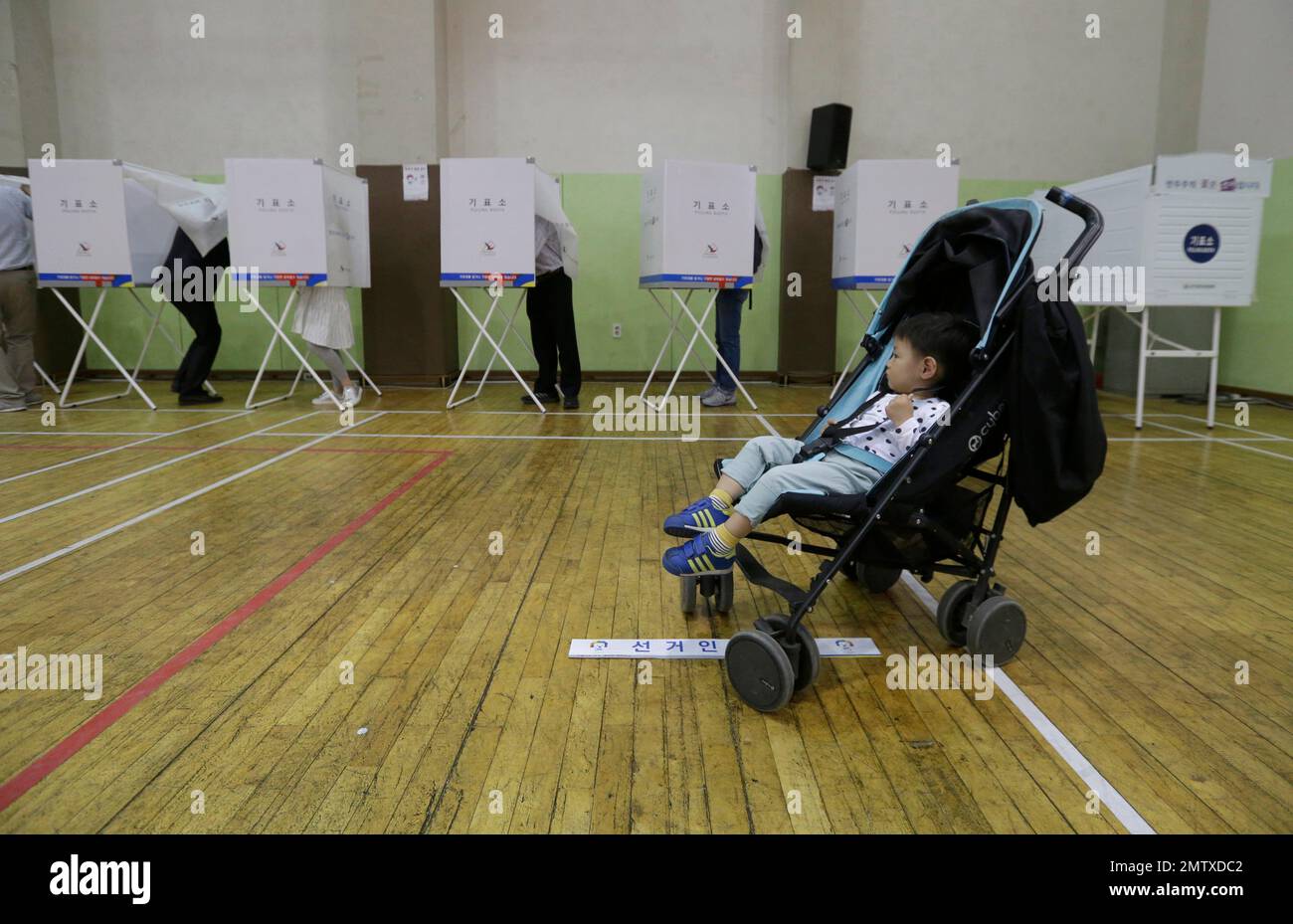 A boy waits for his mother casting her early vote for the May 9 ...