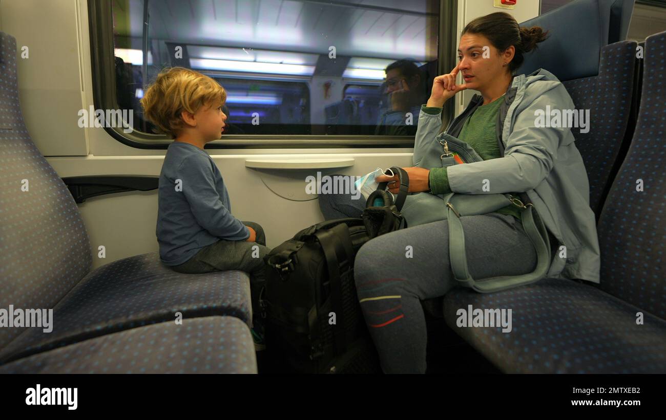 Mother and child traveling by train together little boy listens to mom ...