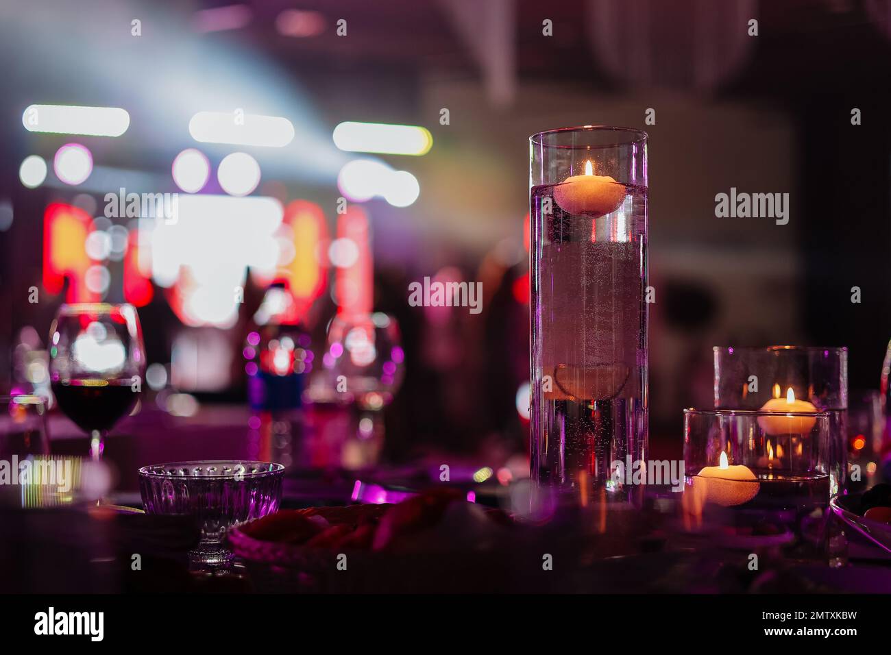 Banquet table decorated with burning candles in glass vases in ...