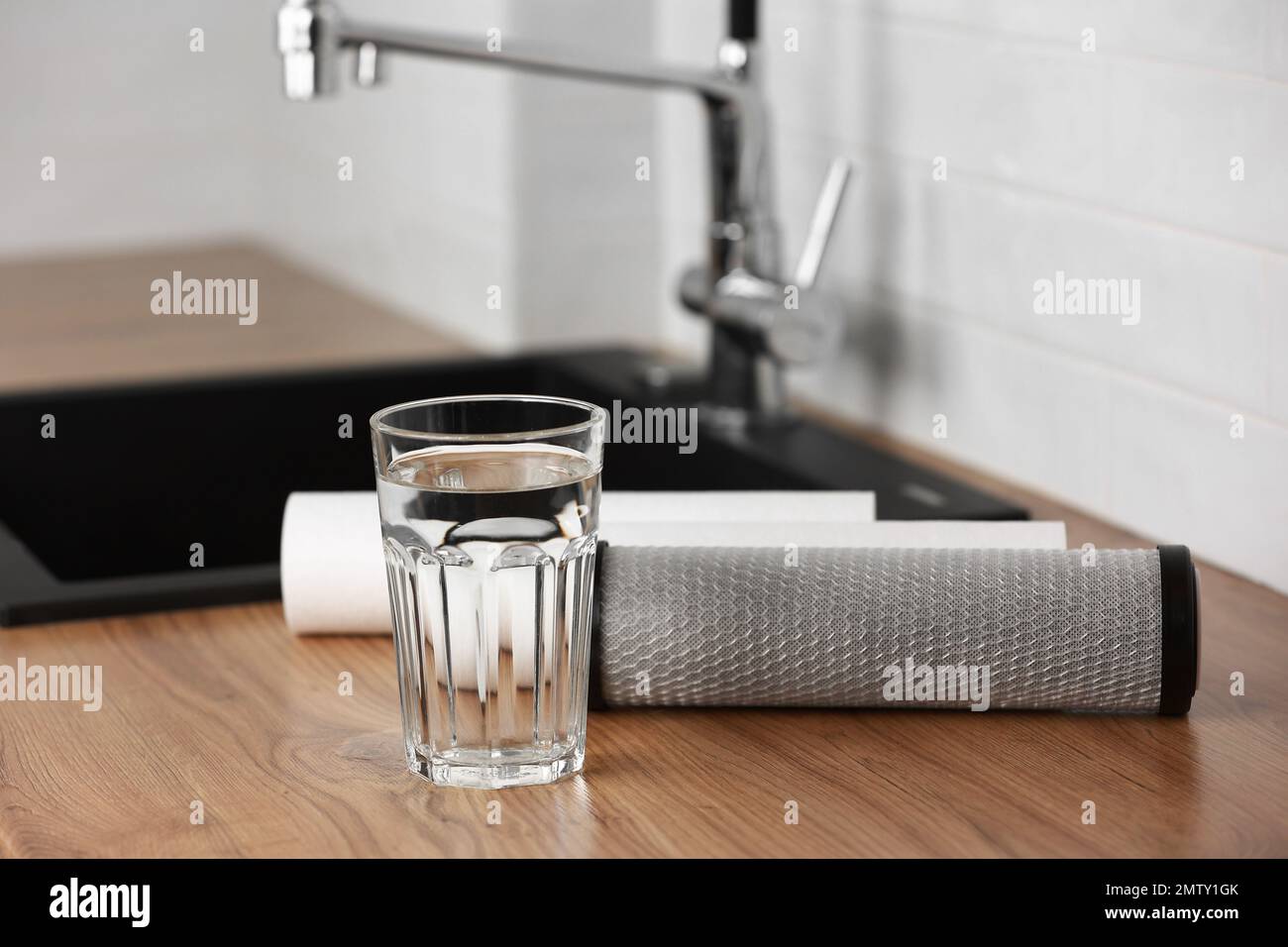 A glass of clean fresh water and set of filter cartridges on wooden ...