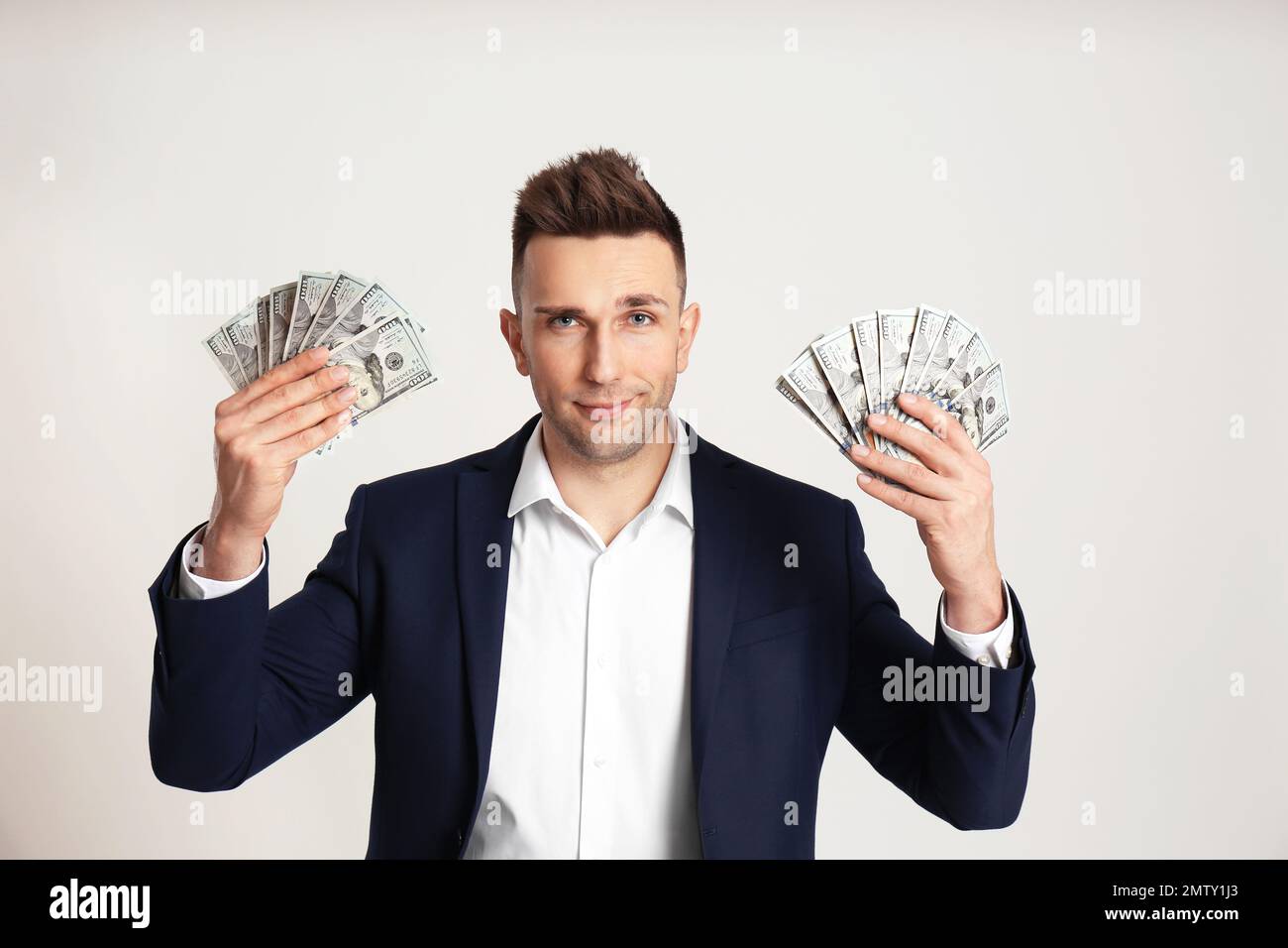 Confident man with cash money on light grey background Stock Photo - Alamy