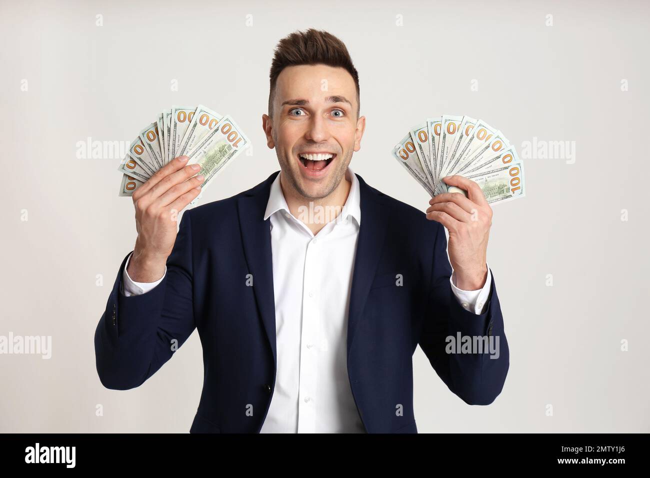 Happy man with cash money on light grey background Stock Photo - Alamy