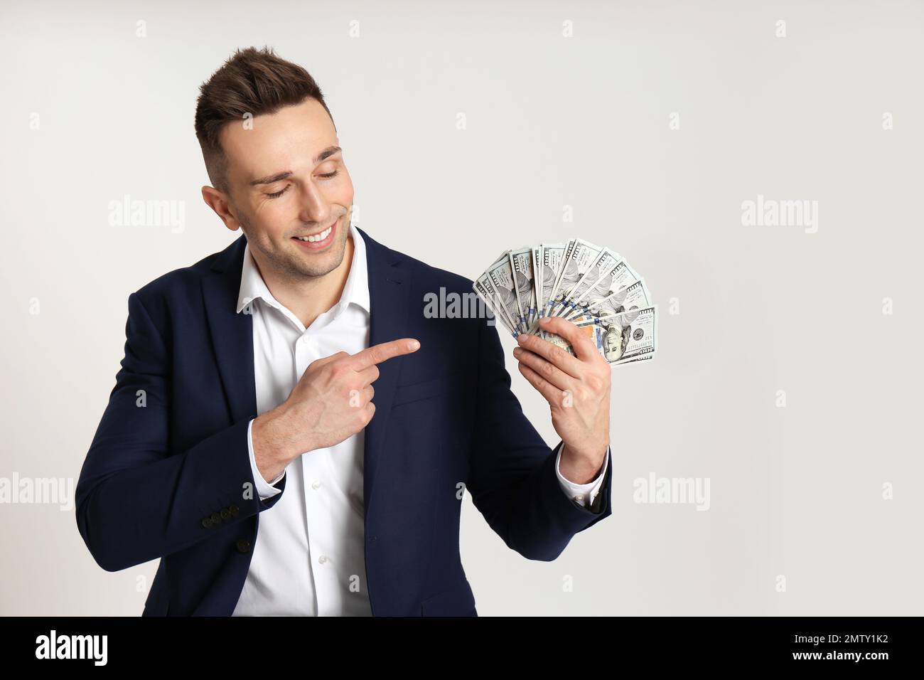 Happy man with cash money on light grey background Stock Photo - Alamy