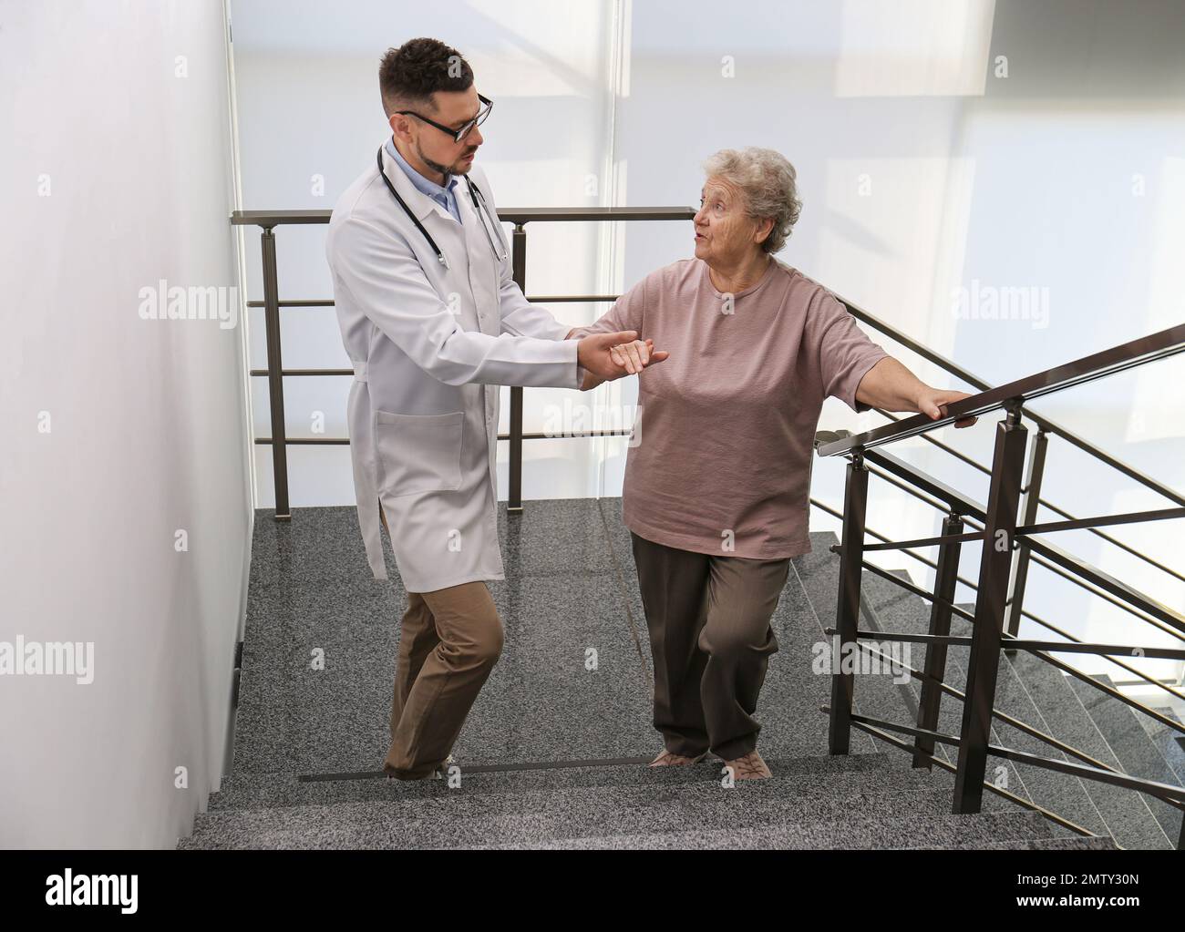 Doctor helping senior patient in modern hospital Stock Photo - Alamy