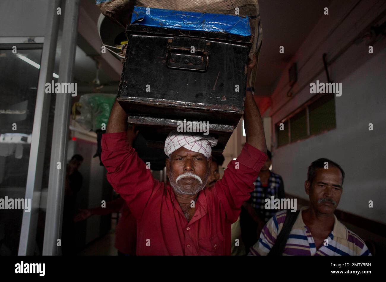 An Indian porter carries luggage on a railway platform during May Day ...