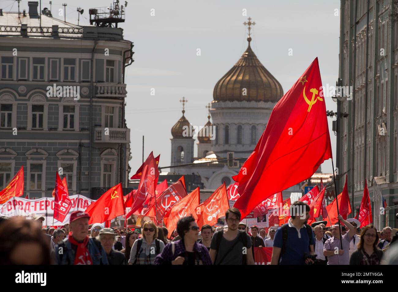People march with red flags with the Christ the Savior Cathedral in the ...