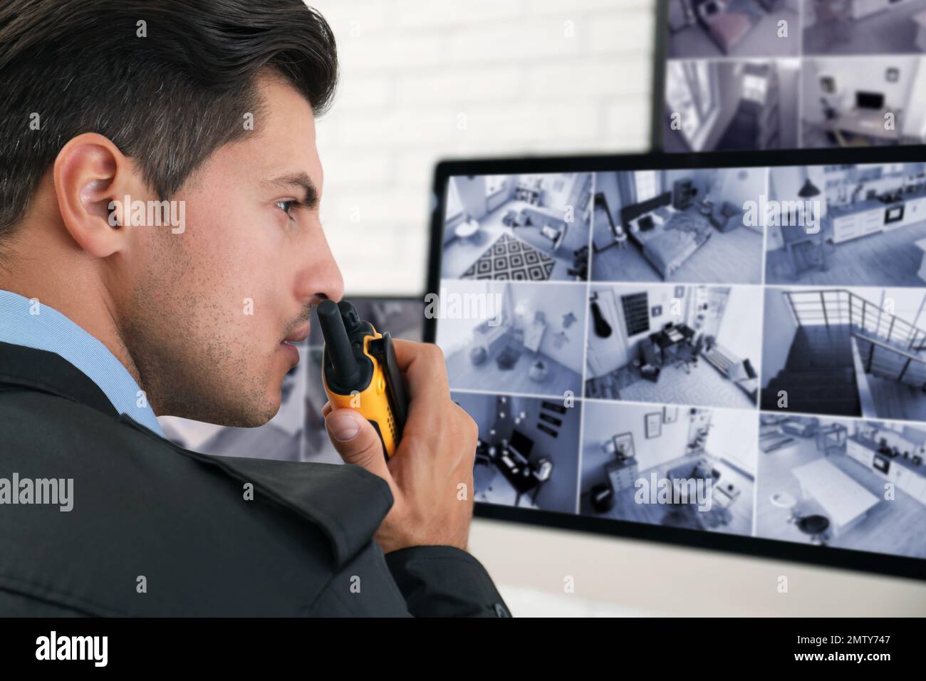 Male security guard with portable transmitter near monitors at ...