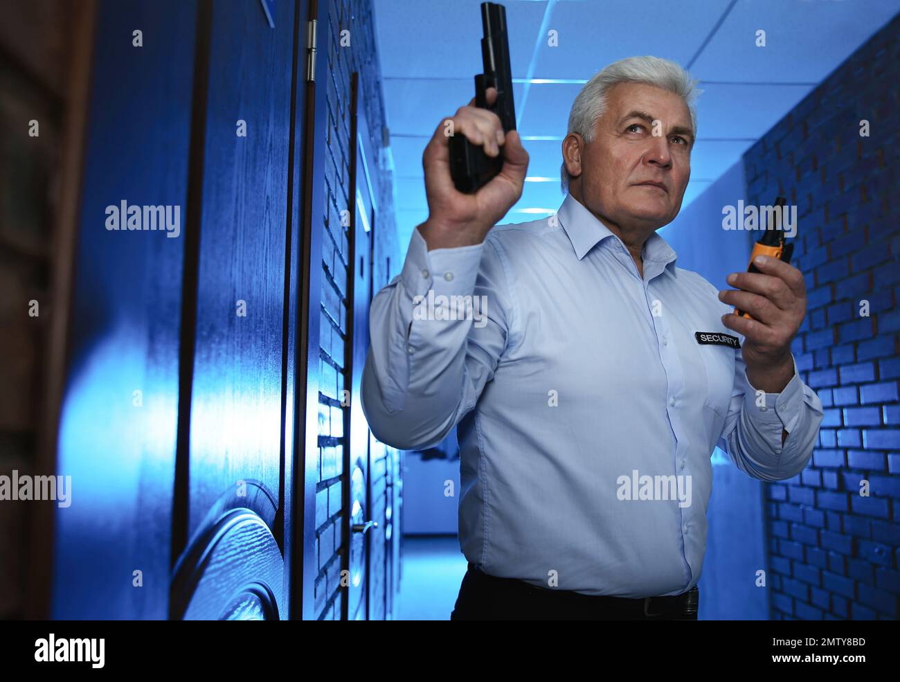 Professional security guard with gun and portable radio set in dark ...