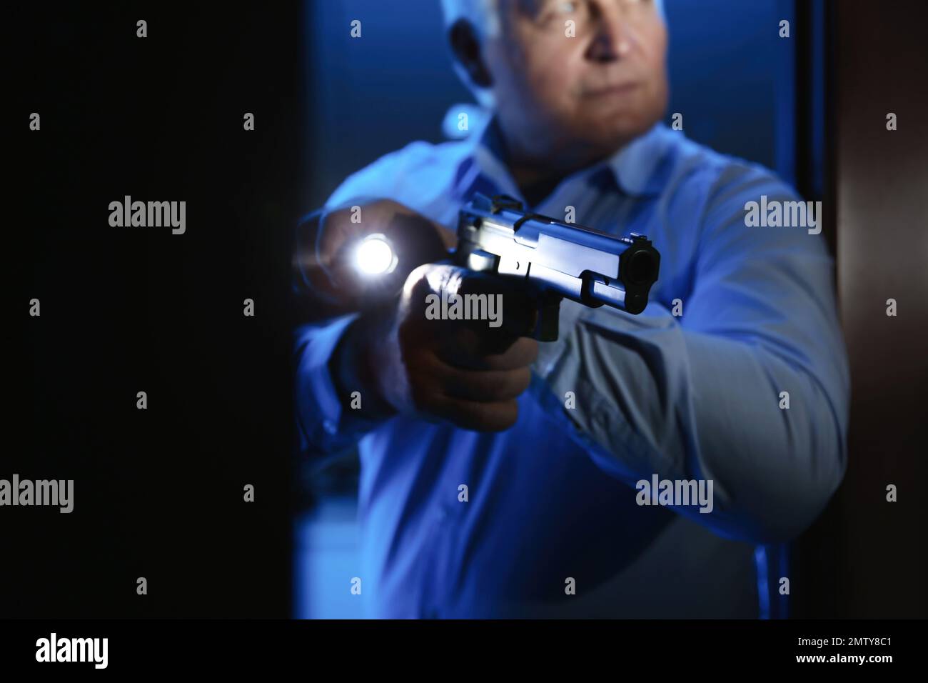 Professional security guard with gun checking dark room, focus on hand ...