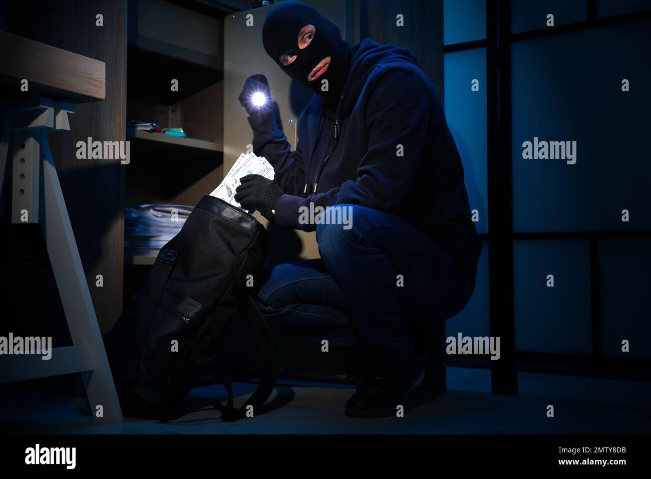 Thief taking money out of steel safe indoors at night Stock Photo - Alamy