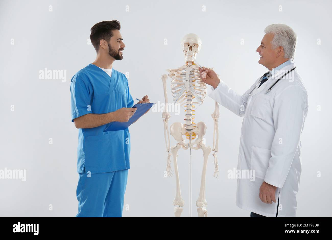 Professional orthopedist with human skeleton model teaching medical ...