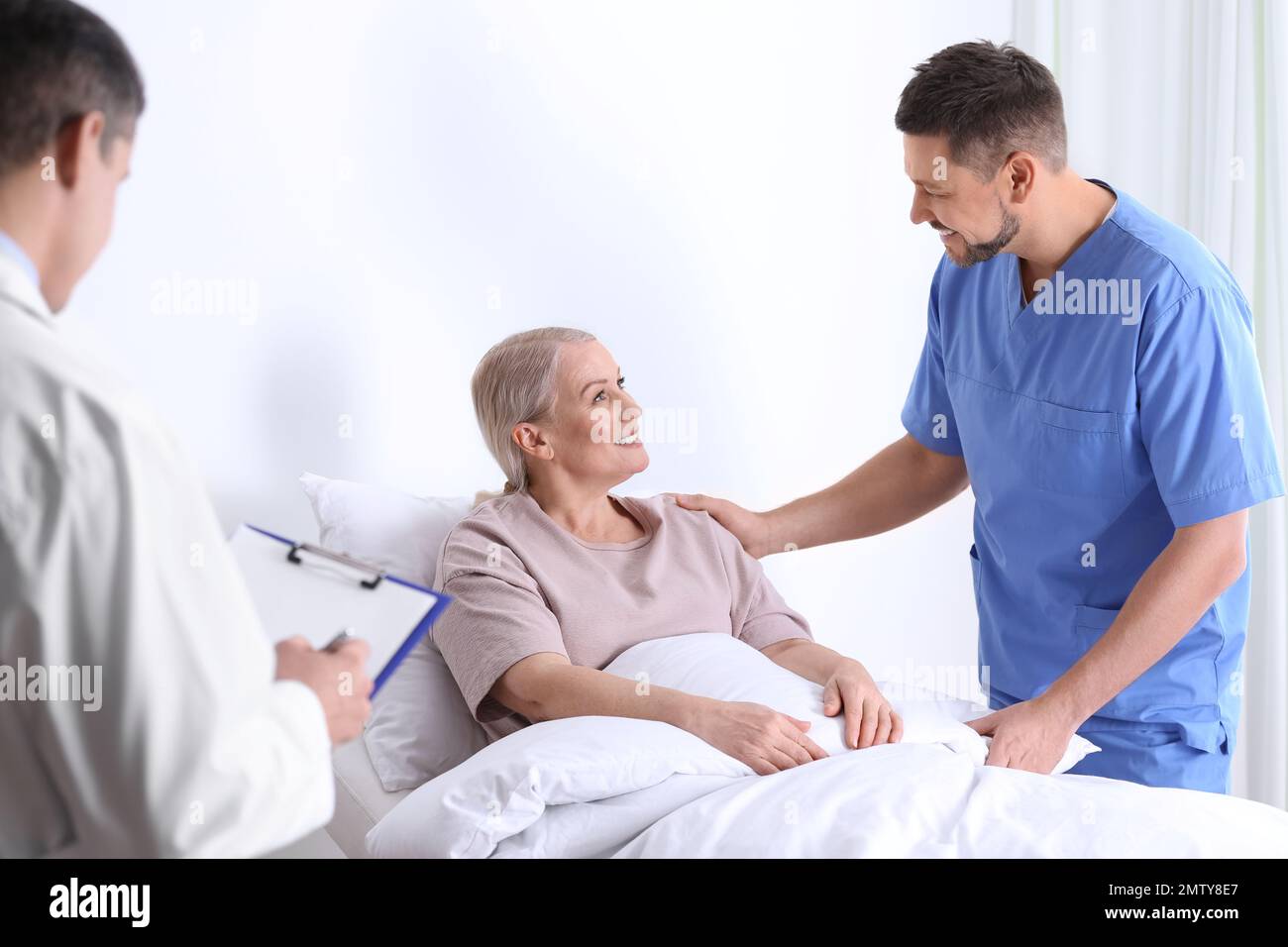 Doctor and male nurse visiting patient in hospital ward Stock Photo - Alamy