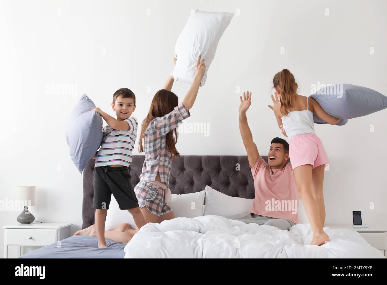 Happy family having pillow fight in bedroom Stock Photo - Alamy