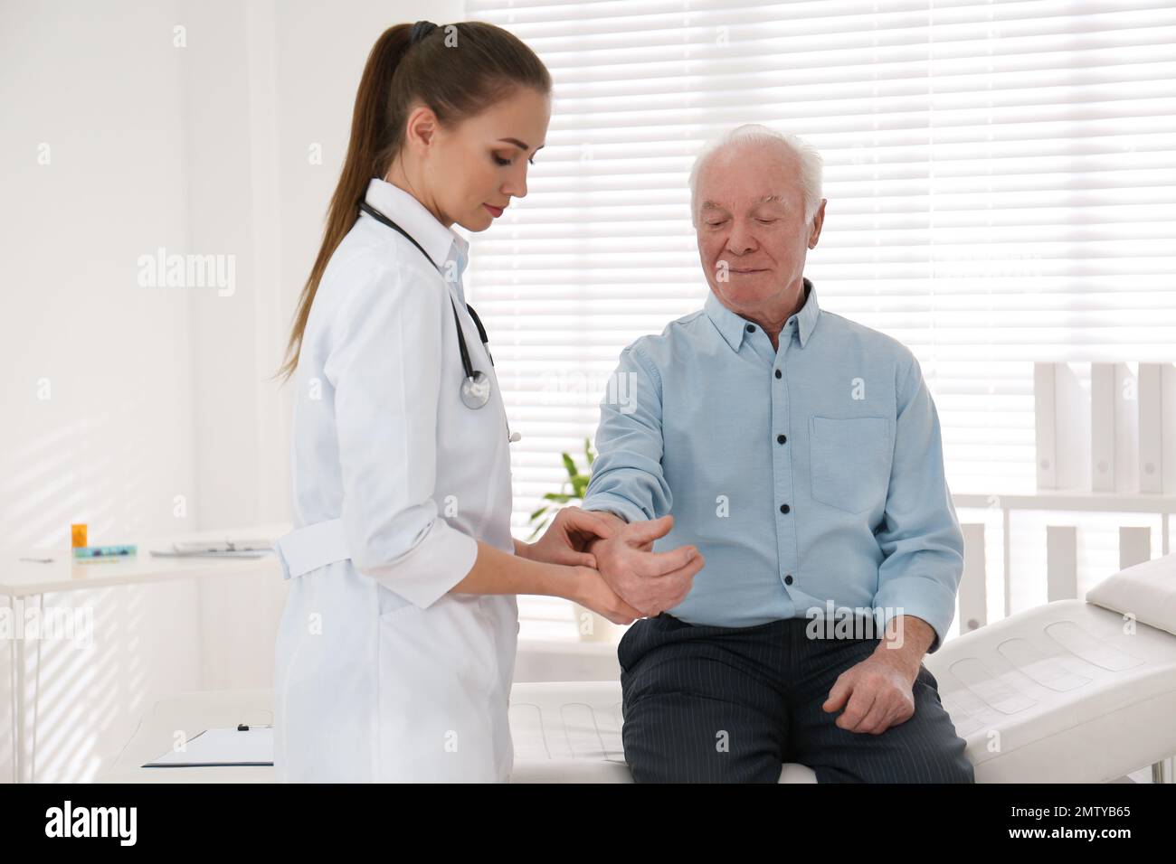 Doctor checking pulse of senior patient in office Stock Photo - Alamy