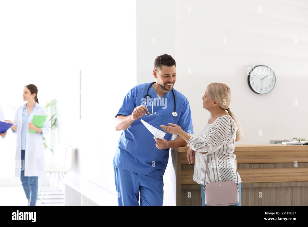 Doctor talking with patient in hospital hall Stock Photo - Alamy