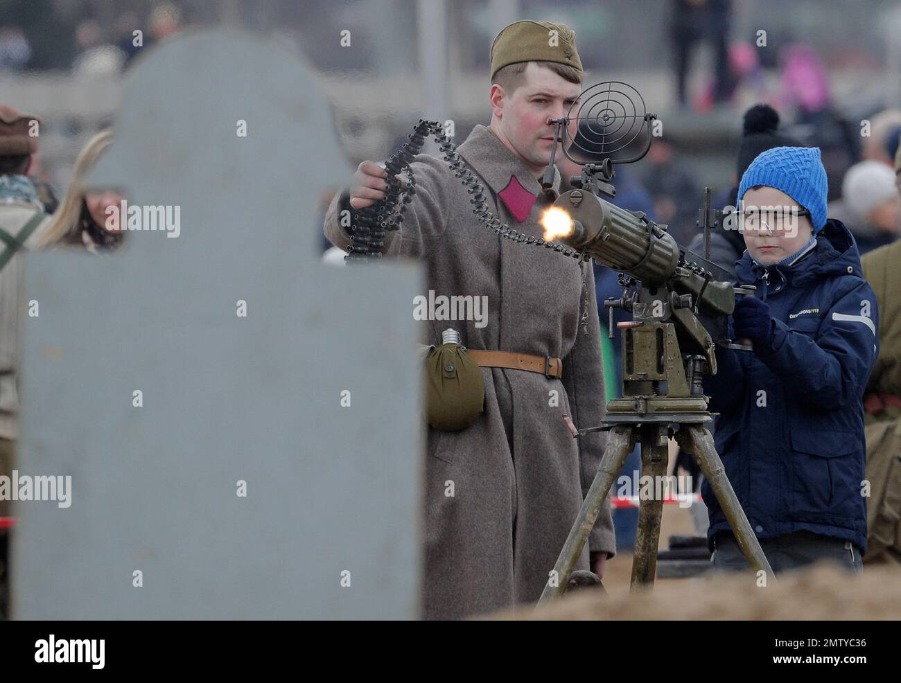 A military instructor wearing Soviet army uniform helps a boy to shoot ...