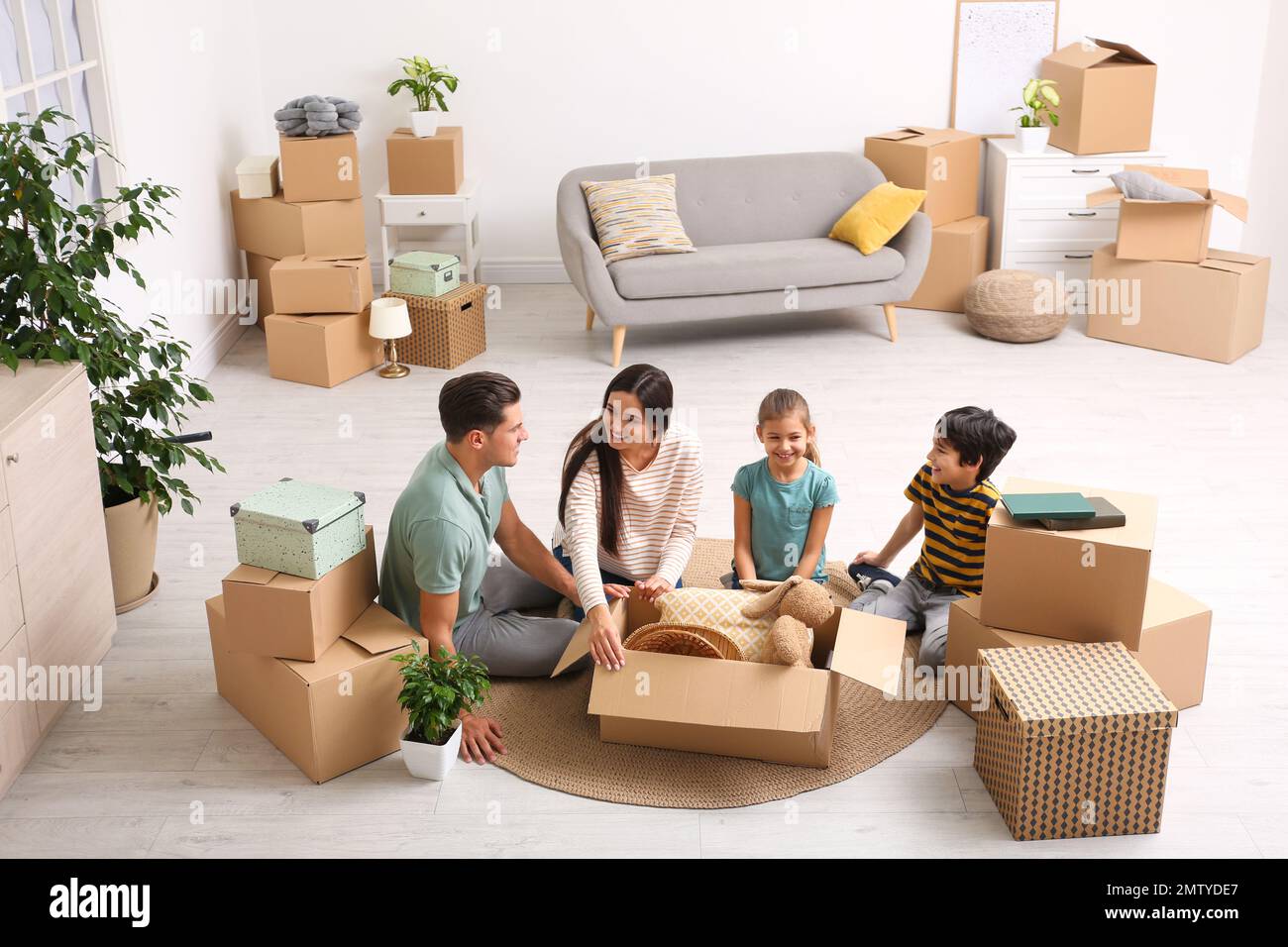 Happy family unpacking moving boxes at their new home Stock Photo - Alamy
