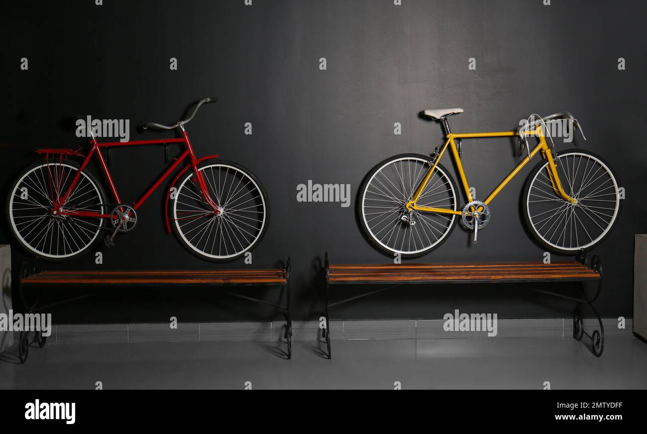 Color bicycles hanging on black wall indoors Stock Photo - Alamy