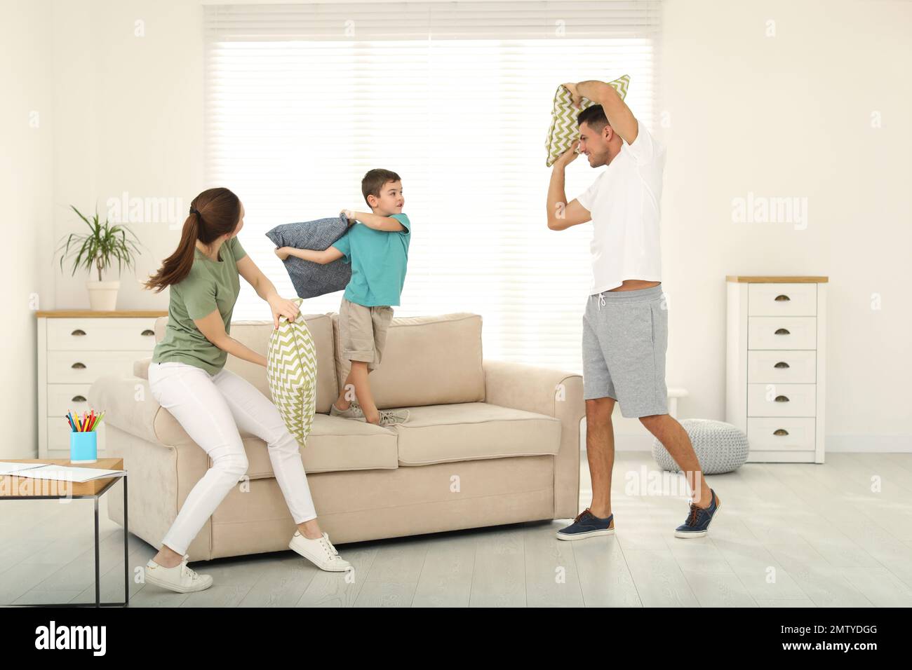 Happy family having pillow fight in living room Stock Photo - Alamy