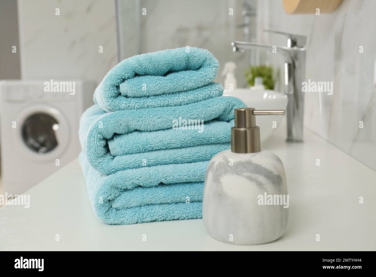 Stack of clean towels and soap dispenser on countertop in bathroom ...